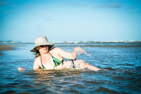 Premium Photo Mature Woman In A Bikini And Hat Bathing In The Sea On