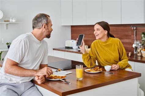 Mujer Feliz Mostrando Su Smartphone A Su Marido Imagen De Archivo