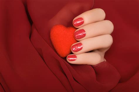 반짝이는 빨간 네일 디자인의 여성 손 붉은 매니큐어 매니큐어 여자 손 잡고 빨간 마음 에 빨간 직물 배경 개념에 대한 스톡 사진 및 기타 이미지 Istock