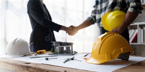 shaking hands blueprints architects and building engineers talking