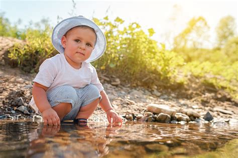 화창한 날에 자연에서 모자를 쓰고 호수 나 강가에서 바위와 물을 가지고 노는 장난 어린 소년 아이의 초상화 2 3 살에 대한 스톡 사진 및 기타 이미지 Istock