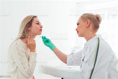 젊은 여성 미용사는 새로운 얼굴 피부 관리 절차에 대한 젊은 금발의 여자와 이야기 얼굴 피부를 검사 전문 미용사 35 39세에