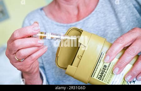 Woman Disposing Of A Used Needle In A Sharpsguard Disposal Waste Unit Or Sharps Bin Stock Photo