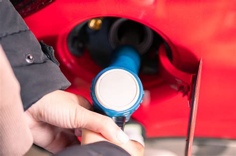 자동차 여행 중 주유소에서 빨간 자동차의 가스 탱크에 호스로 연료를 보급하는 여자의 손의 관점 액화천연가스에 대한 스톡 사진 및 기타 이미지 Istock