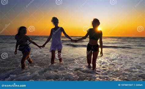 Group Of Female Teens Having Fun Jumping And Splashing Down The Beach