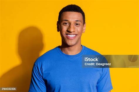 ภาพบุคคลของชายหนุ่มสวยดูกล้องยิ้มฟันสวมใส่ชุดสีน้ําเงินอินเทรนด์แยกบนพื้นหลังสีเหลือง ภาพสต็อก