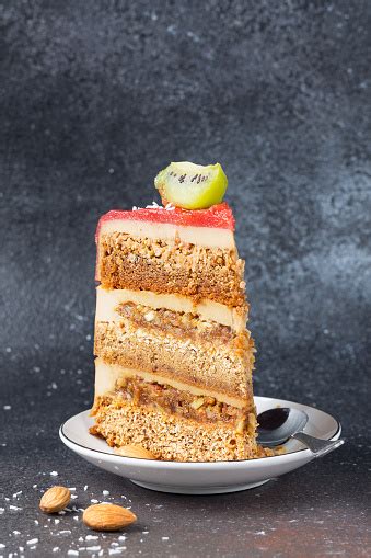 어두운 배경에 딸기 아이싱 코코넛 칩 아몬드가 있는 글루텐 프리 케이크 한 조각이 흰색 접시에 새어 있습니다 0명에 대한 스톡 사진 및 기타 이미지 Istock