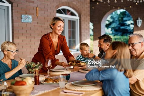 테라스의 식탁에서 가족 점심 식사 중에 음식을 제공하는 행복한 여자 가족에 대한 스톡 사진 및 기타 이미지 가족 남성