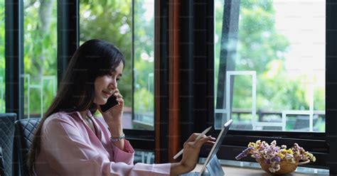 카페테리아의 테이블에서 디지털 태블릿으로 작업하는 동안 전화로 이야기하는 사업가의 측면 모습 사진 Unsplash의 사무실 보기 이미지