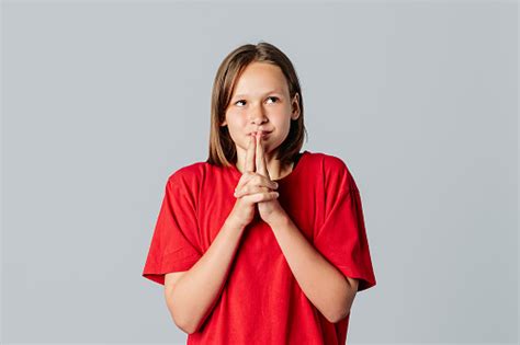 멋진 무언가를 기대 하는 아름 다운 갈색 머리 십대 소녀 소원 을 만들기 캐주얼 빨간 티셔츠에 착용 기적을 기다리는 젊은 여성이 무언가를 희망합니다 10 11세에 대한 스톡