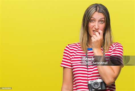 격리 된 배경에 강조 하 고 손톱을 물어 뜯고 입에 손을 긴장을 찾고 빈티지 사진 카메라를 사용 하 여 사진을 찍는 젊은 아름 다운 여자 불안 문제입니다 감정에 대한 스톡