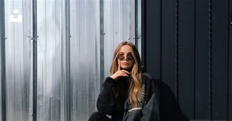 회색 콘크리트 바닥에 앉아 검은 재킷과 흰색 바지를 입은 여자 사진 Unsplash의 무료 도시 이미지