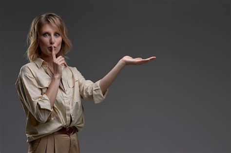 입술에 손가락을 들고 있는 젊은 여성은 복사 공간을 가리키는 조용히 조용히 조용히 복사 공간이있는 회색 빈 스튜디오 배경에 고립 된 서 침묵 속에서 Shh 제스처 비밀을