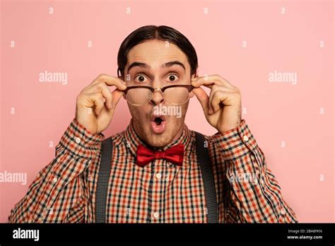 Shocked Male Nerd Holding Eyeglasses Isolated On Pink Stock Photo Alamy