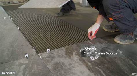 세라믹 바닥 타일을 접착하기위한 접착 솔루션 전문 노동자바닥에 장식 타일을 붙입니다 바닥에 타일을 붙이기위한 산업 규모의 박격포 응용 프로그램 타일에 대한 스톡 사진 및