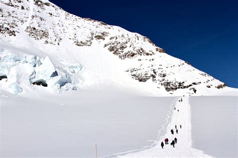 Exws 설원 노출된 빙하와 산 능선이 스위스 베른 알프스의 풍경을 배경으로 작은 인물과 함께 융프라우요흐의 깊고 푸른 하늘을