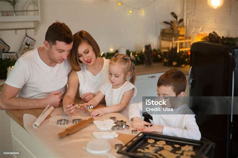 행복한 가족 아빠 엄마 및 두 아이는 크리스마스 쿠키를 만들고 부엌에서 집에서 함께 즐거운 시간을 보냅니다 수제 크리스마스 진저