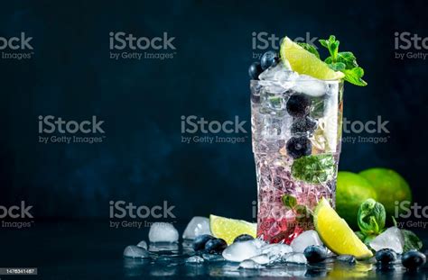 블루 베리 모히토 칵테일 음료는 라임 화이트 럼 소다 지팡이 설탕 민트 얼음이 진한 파란색 배경에 유리에 담겨 있습니다 여름 상쾌한 음료 Gin Tonic에 대한 스톡 사진