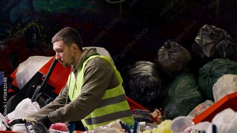 Portrait Of Concentrated Male Worker In Gloves And Safety Vest Sorting Garbage On Sorting Line