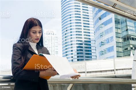 비즈니스 아시아 여자의 느낌에서의 스트레스를 집중 하 고 서 고 종이 파일 외부 현대 외관 건물의 시 공간으로 야외 보행자 도보 방법에 시트를 참조 하십시오 거리에 대한