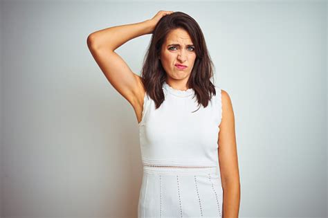 흰색 고립 된 배경 위에 서있는 드레스를 입은 젊은 아름다운 여성은 혼란스럽고 질문에 대해 궁금해합니다 의심의 여지가 머리에 손으로 생각 펜시브 개념 개념에 대한 스톡 사진