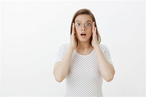 Удивленная и удивленная женщина в очках с волнением слушает Бесплатно Фото