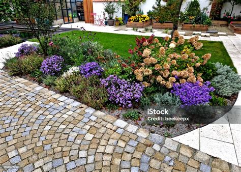 가을에 여러 개의 화단 화단 일년생 및 다년생 식물이 있는 가족 정원의 구석구석은 여전히 화려하고 멋지게 조화를 이룹니다 영국 스타일의 차고 옆 마당 현대 뒤뜰 앞마당 또는