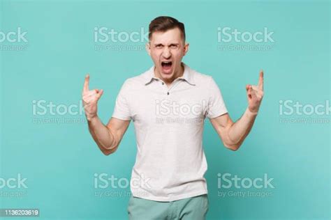 제스처 스튜디오에서 파란색 청록색 배경에 고립 된 무거운 금속 바위 표지판을 묘사 캐주얼 옷에 젊은 남자를 비명 사람들은 진심으로 감정 라이프 스타일 개념입니다 복사 공간을