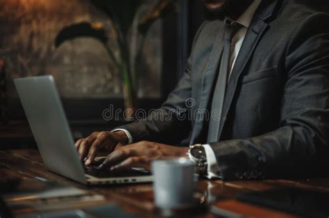 A Man In A Suit Sitting At A Desk And Typing On A Laptop Computer A