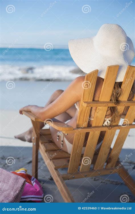Женщина в соломенной шляпе ослабляя в шезлонге на пляже Стоковое Фото изображение