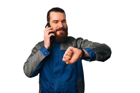 Premium Photo Handsome Bearded Handyman Is Talking On The Phone And Checking His Wrist Watch