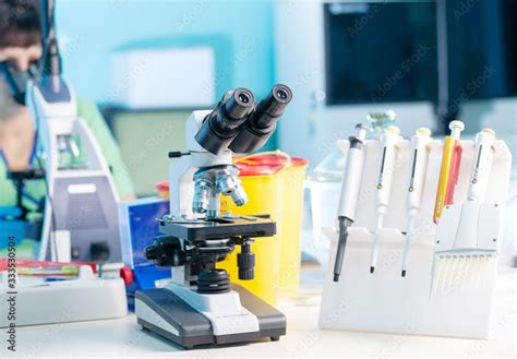 Automatic Pipettes Female Professional In Uniform Work With Light Microscope In Research