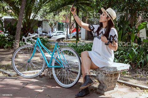 공원에서 셀카를 찍고 옆에 자전거가 달린 흰색 드레스와 모자를 쓰고 있는 소녀 30 34세에 대한 스톡 사진 및 기타 이미지 30 34세 건강한 생활방식 걷기