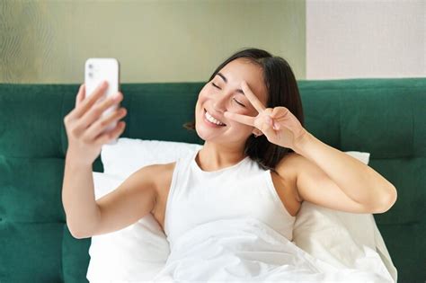 Free Photo Positive Girl Blogger Takes Selfie In Her Bed Bedroom