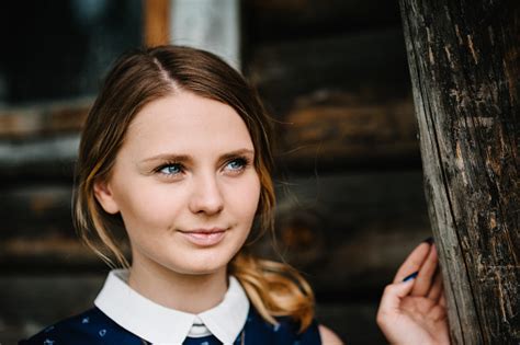 세로 젊은 아름 다운 소녀는 오래 된 집의 나무 벽 옆에 서 있습니다 닫습니다 옆을 바라보 고 있습니다 길이 헤드샷 가을에 대한