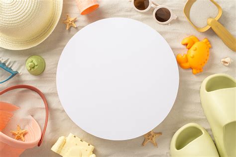 바닷가에서 아이들과 함께하는 즐거운 휴가 파나마 모래 장난감 야자수 잎 조개껍데기 슬리퍼 선글라스가 있는 평면도 사진으로 원 안에 복사 공간이 있는 고립된 모래 배경에