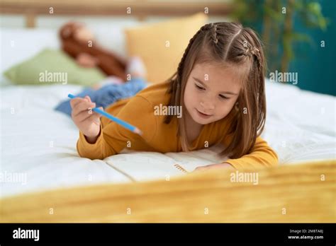 Adorable Hispanic Girl Drawing On Notebook Lying On Bed At Bedroom
