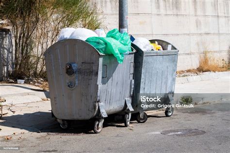 도시의 도로에있는 금속 쓰레기통은 모든 종류의 쓰레기로 가득합니다 인간 오염 폐기물과 쓰레기의 상처 및 재활용을위한 지정된 지역 산업 폐기물 수거통에 대한 스톡 사진 및