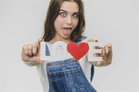 젊은 아름 다운 소녀는 회색 배경에 있습니다 데님 수트와 화이트 티셔츠를 입고 사랑의 말씀으로 표지판을 들고 있다 T 셔츠에 대한 스톡 사진 및 기타 이미지 Istock