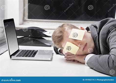 Businessman Sleeping With Sticky Notes On Eyes At Desk In Office Stock