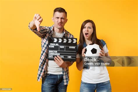 젊은 커플 여자 남자 축구 팬 지원 기운 흥분된 축구공 영화 Clapperboard 노란색 배경에 고립 된 만들기와 팀 스포츠 가족 레저 라이프 스타일 개념입니다 스튜디오