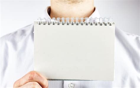 Premium Photo A Man In A White Shirt Holds A Notebook With A Blank