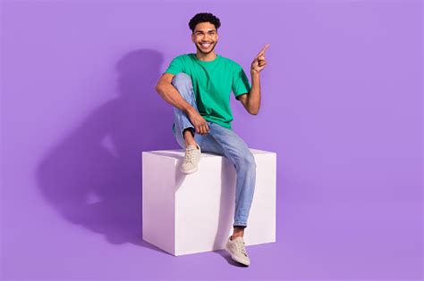 손가락 빈 공간을 지시하는 젊은 남자의 전체 길이 사진 유용한 팁은 보라색 배경에 격리된 플랫폼 브랜드 프로모터에 앉아 있다 18 19세에 대한 스톡 사진 및 기타 이미지