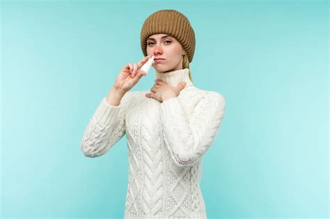 스카프와 모자에 아픈 젊은 여자는 파란색 배경에 고립 된 비강 스프레이를 사용 감기와 독감에 대한 스톡 사진 및 기타 이미지