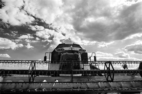 현대식 콤바인 수확기가 수확하는 동안 들판에 서 있습니다 힌지 프레임에 광각 렌즈가 있는 하단 View 커터바 드레이퍼 결합 헤더 흑백 사진입니다 경첩에 대한 스톡 사진 및