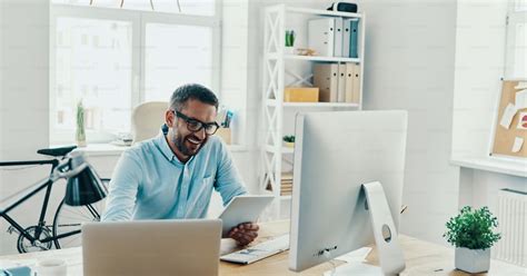 디지털 태블릿을 사용하고 사무실에 앉아 웃고 있는 스마트 캐주얼 옷을 입은 잘생긴 중년 남자 사진 Unsplash의