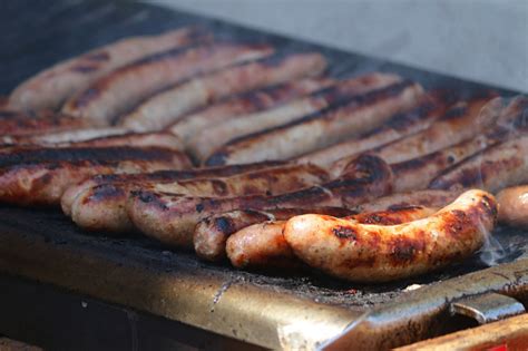 정원 파티 숯불 바베큐 큰 소시지의 이미지 행 요리 철판 그릴에 완벽하게 굽기 불타는 연기 각 소시지를 돌리는 통을 제공하는 햄버거와 연기가 자욱한 바베큐 거리 시장