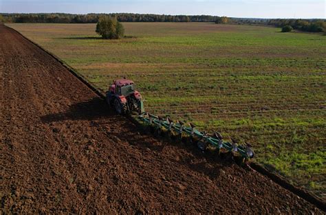 쟁기 위에 쟁기 트랙터 쟁기질과 토양 틸리지 파종 씨앗에 대한 재배 필드에 농업 트랙터 일몰 동안 필드 재배 하는 동안 큰 트랙터 쟁기밭의 트랙터 0명에 대한 스톡 사진 및