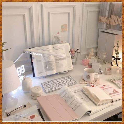 A White Desk Topped With Lots Of Books And A Computer Monitor Next To A Lamp