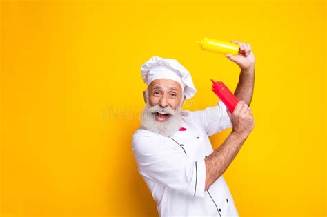 Cheerful Senior Chef In A Bright Uniform Posing With Condiment Bottles Cheerful Senior Chef In A Bright Uniform Posing With Condiment Bottles
